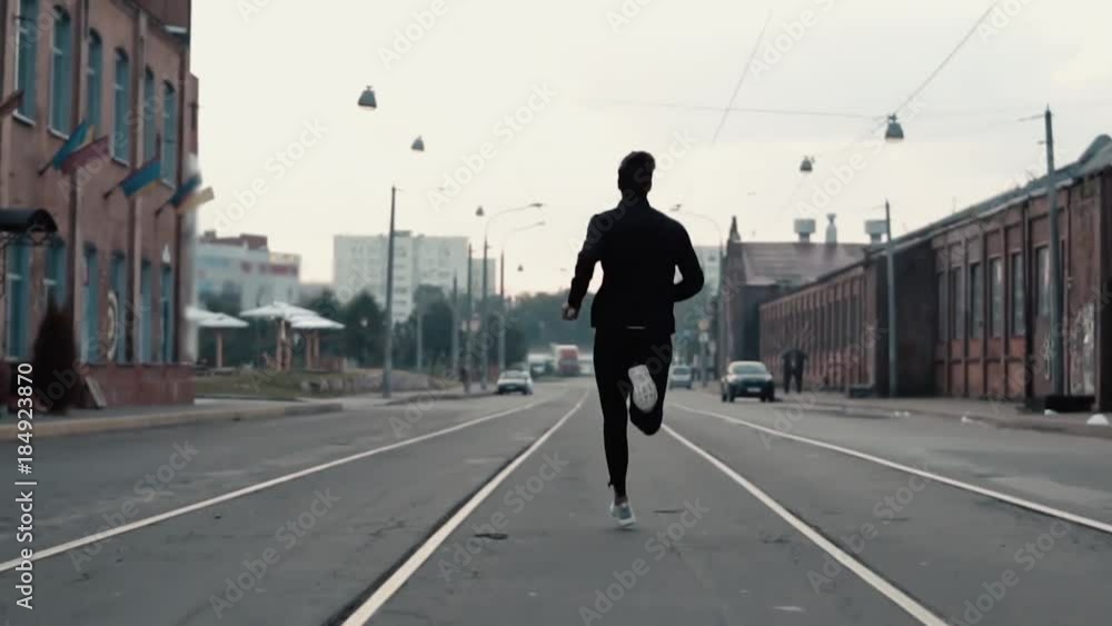 Man running fast in the middle of an old street. Real time shot ...