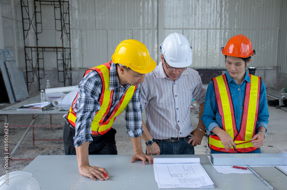Top view of group of engineering team is meeting, planning construction work,looking paper plans ...