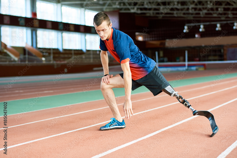 Full length portrait of young amputee athlete warming up before running ...