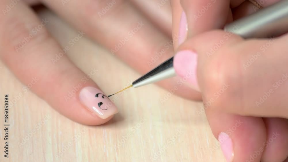 Manicurist drawing on female nails. Manicure specialist doing beautiful ...