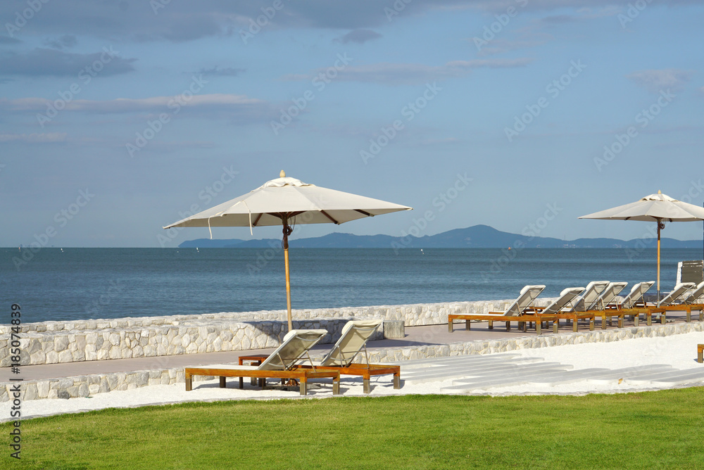 White color recliner beach seating with white parasol facing the sea ...