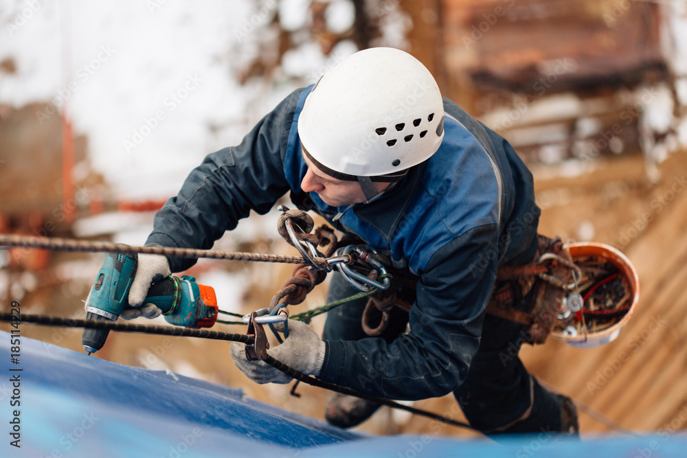 Foto de Professional industrial climber in helmet and uniform works at ...
