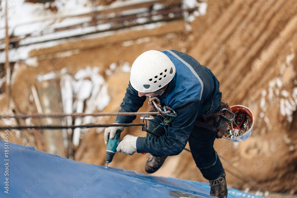 Professional industrial climber in helmet and uniform works at height ...
