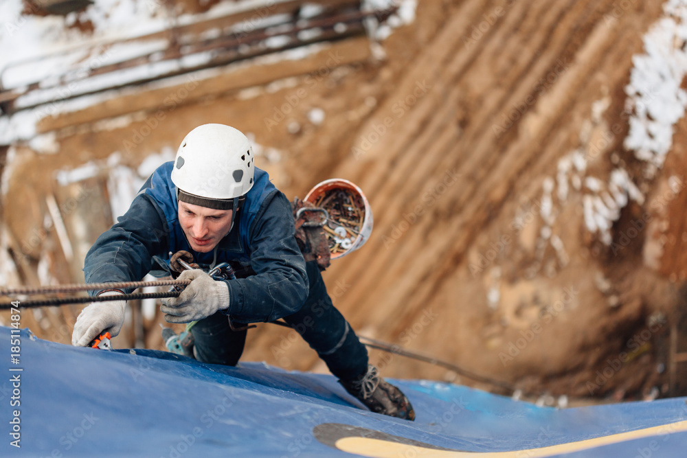 Professional industrial climber in helmet and uniform works at height ...