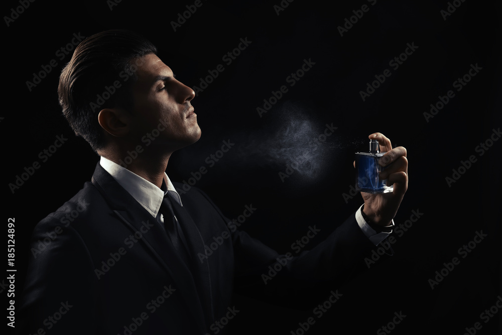 Handsome man with bottle of perfume on dark background Stock Photo ...
