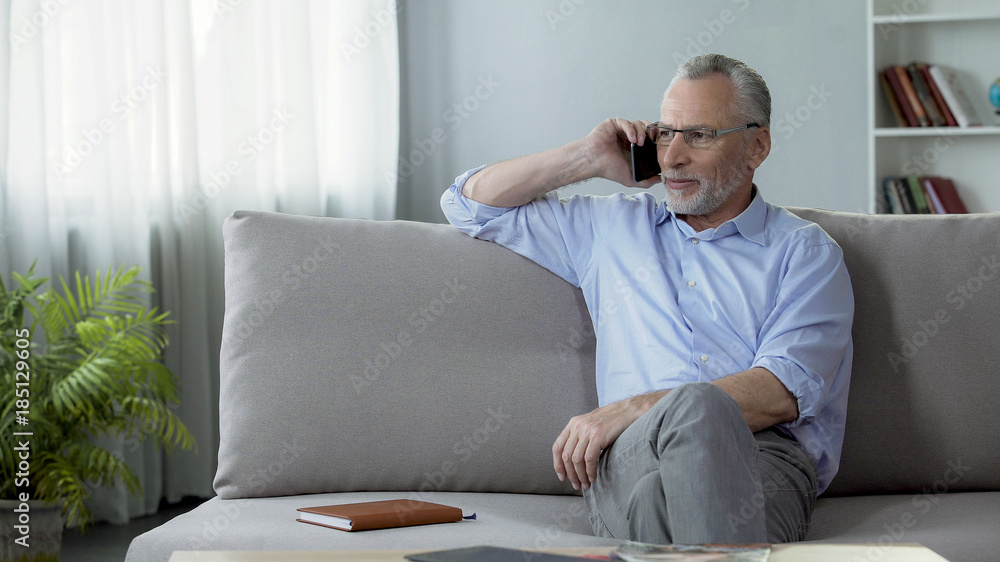 Caring retired father sitting on sofa and calling his children ...
