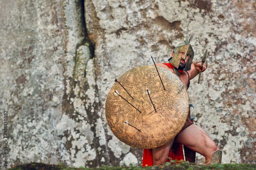 Shot of a brave Spartan protecting himself with a shield holding a ...