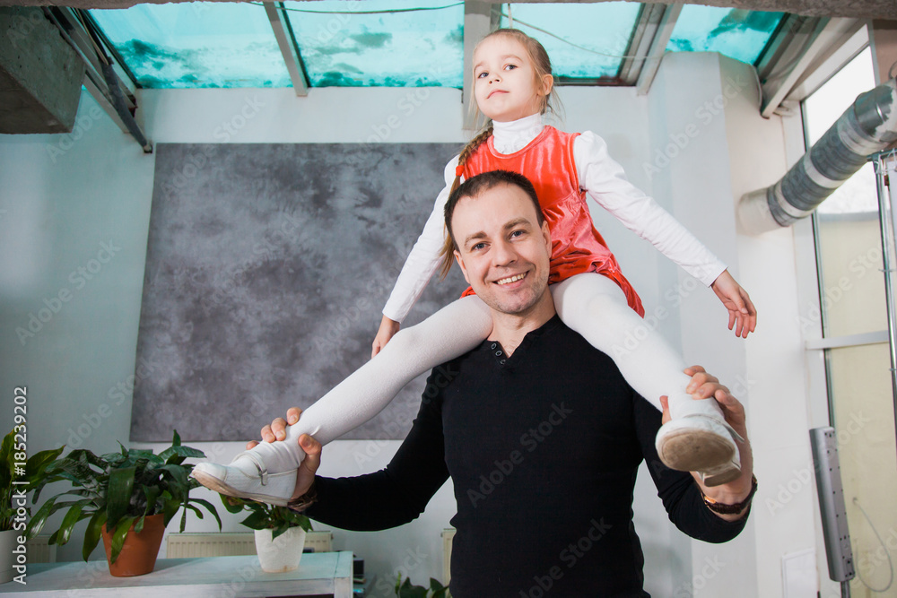 Father and daughter having fun together playing a shoulder ride indoors ...
