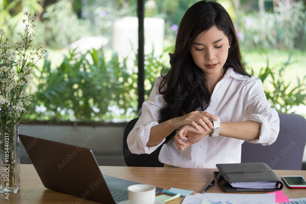 businesswoman look at her watch at workplace. startup woman check time ...