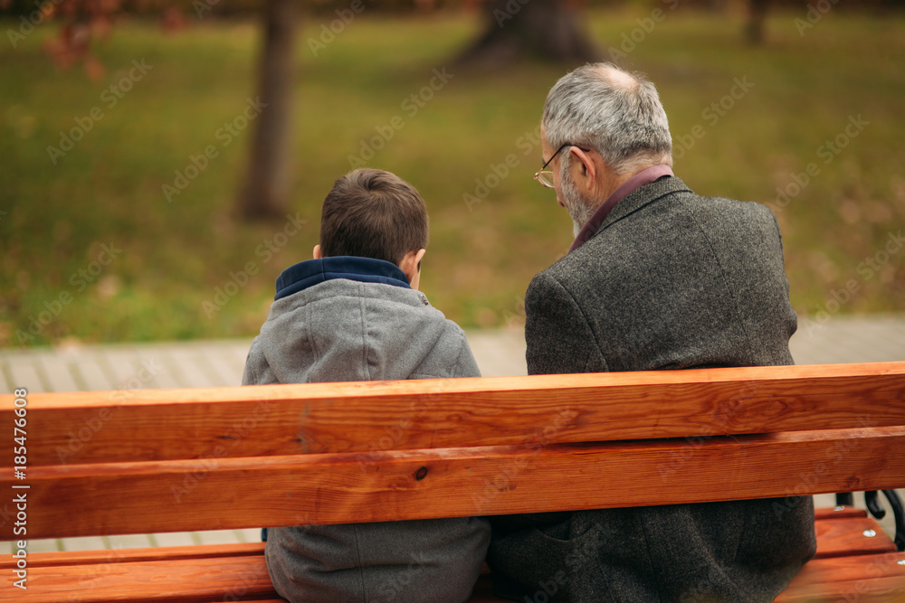Grandpa and his grandson spend time together in the park. They are ...