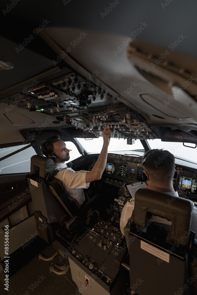 Pilot and copilot flying an airplane Stock Photo | Adobe Stock