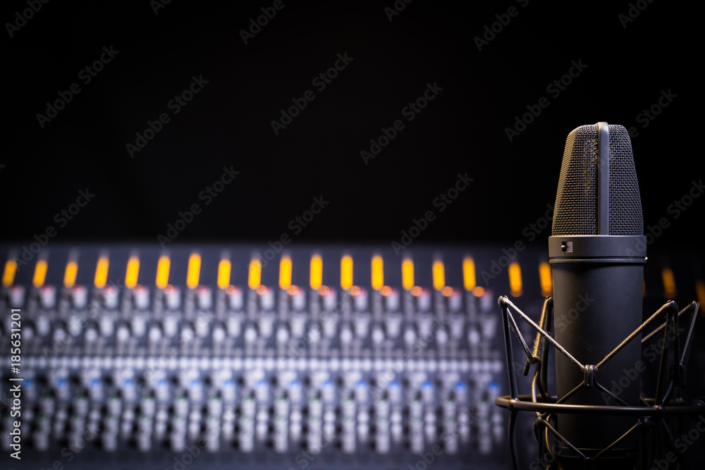 Recording studio scene with close up microphone and soft focus mixer ...
