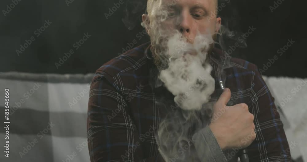 relaxing chilling man inhaling and exhaling hookah smoke, sitting in ...