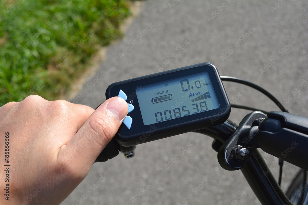 A male hand presses a button on a black electronic bicycle scooter ...