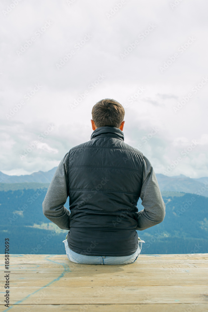 boy man sitting on top of the mountain Back. looking at the mountains ...