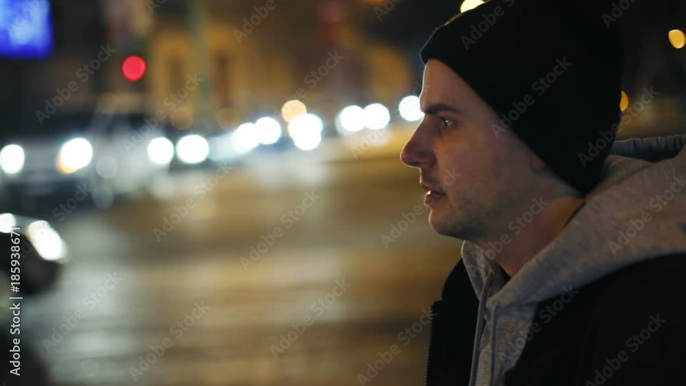 Attractive young man standing outside city night time street cars light ...