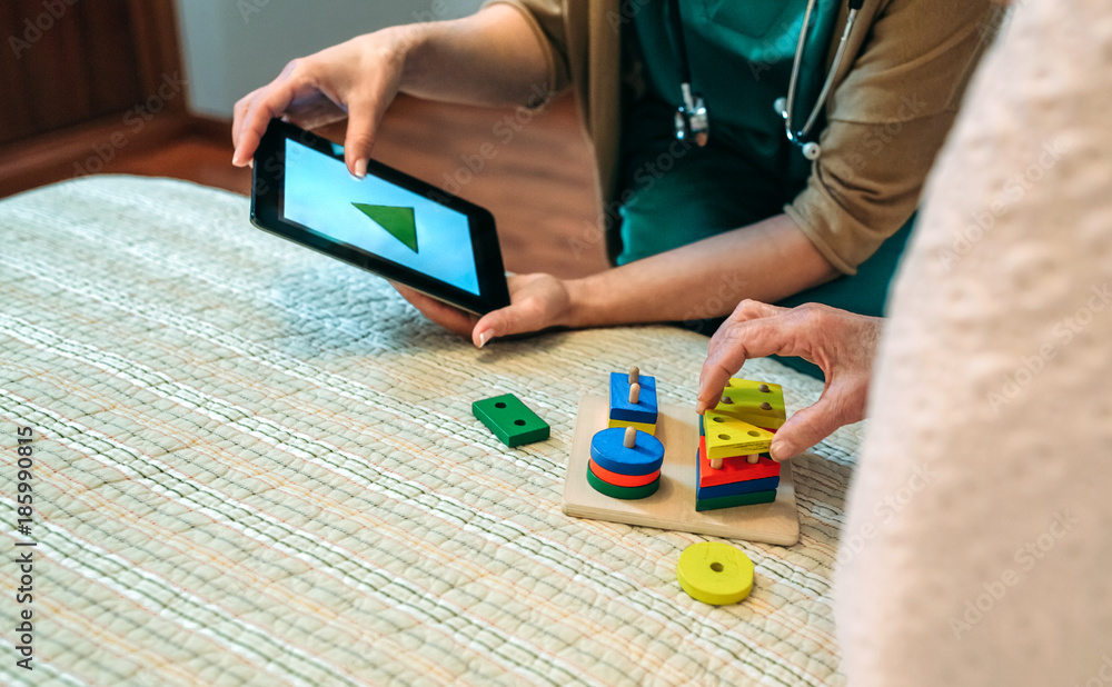 Female doctor showing geometric shape game to elderly female patient ...