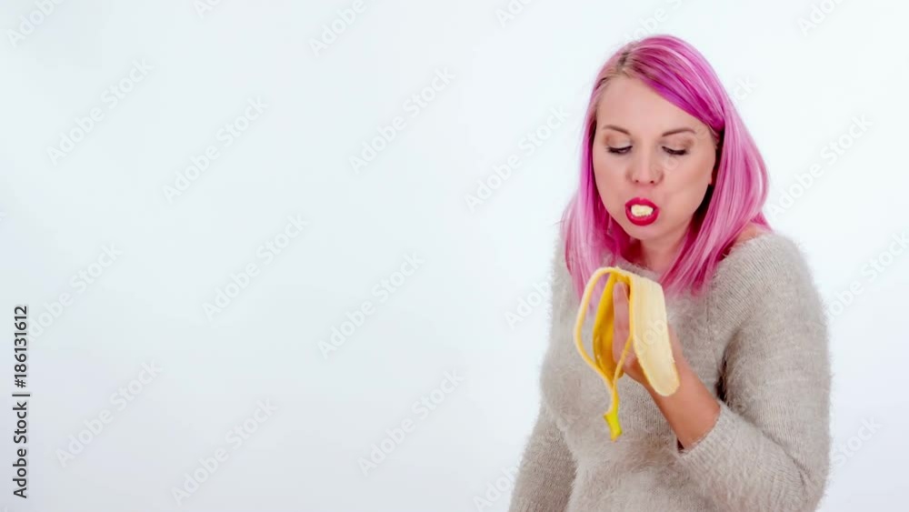 A young woman is finishing eating a banana and then she is dropping the ...