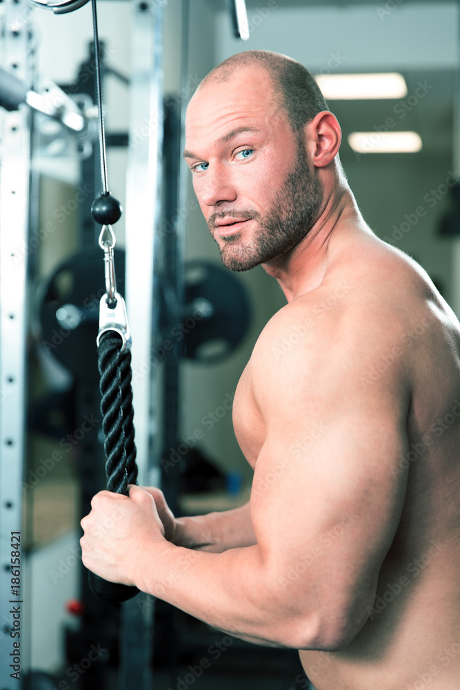 Junger Bodybuilder trainiert im Fitnessstudio seine Muskeln mit ...