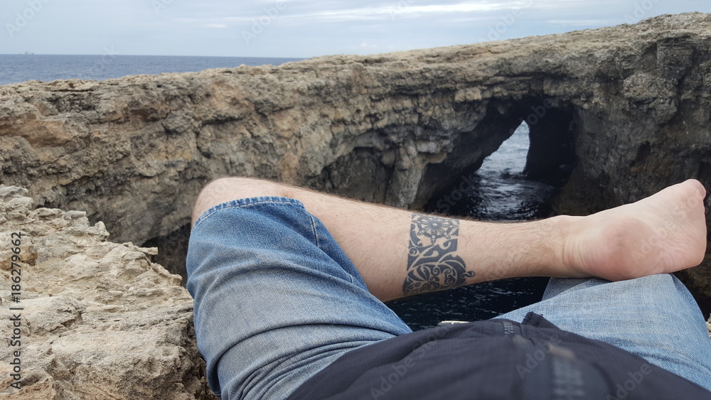 man sitting on the top of the sea cave - dragonara cave - coral lagoon ...
