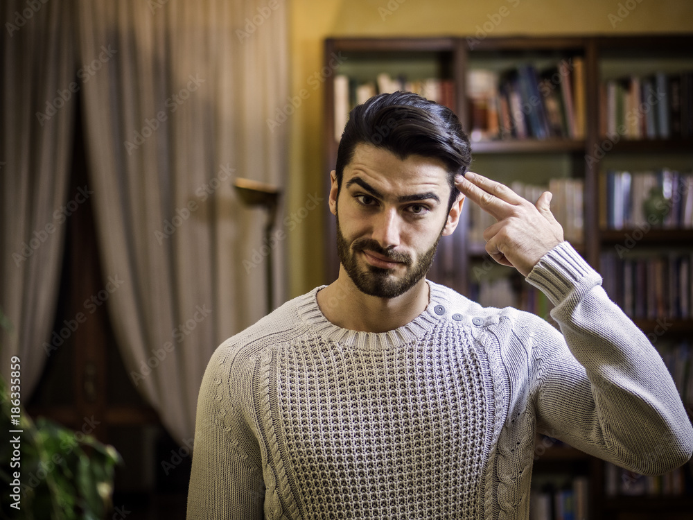 Sad attractive young man standing with a serious expression pointing an ...