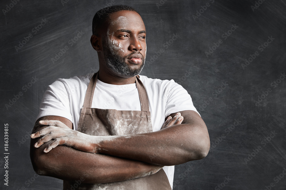 Foto de Thoughtful dark skinned male model wears apron, has dirty face ...