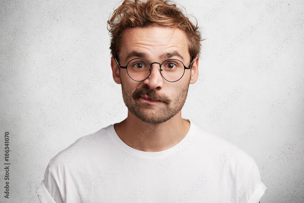Isolated shot of indignant bearded male curves lips, looks in ...