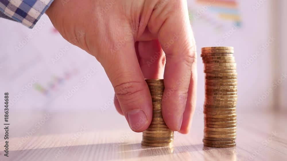 Man hand holding coin dollar on money coin stack arranged as a graph on ...