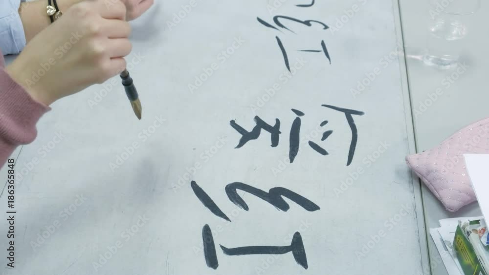 Woman teaching teen how to write Chinese characters at calligraphy ...