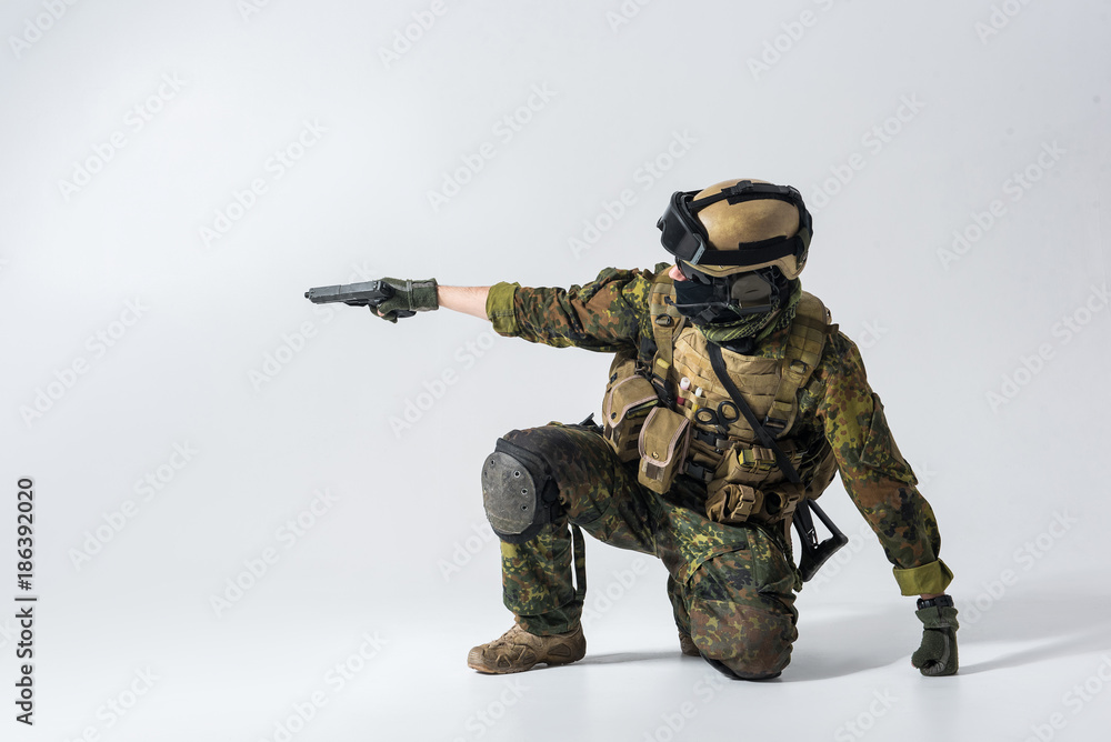 Side view severe soldier firing with pistol while wearing balaclava and ...