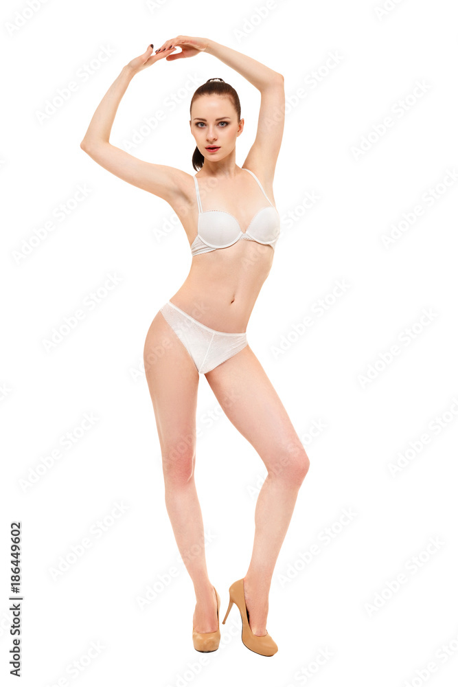 The girl is standing with her hands up. A fashion model posing in her underwear. Isolated on ...