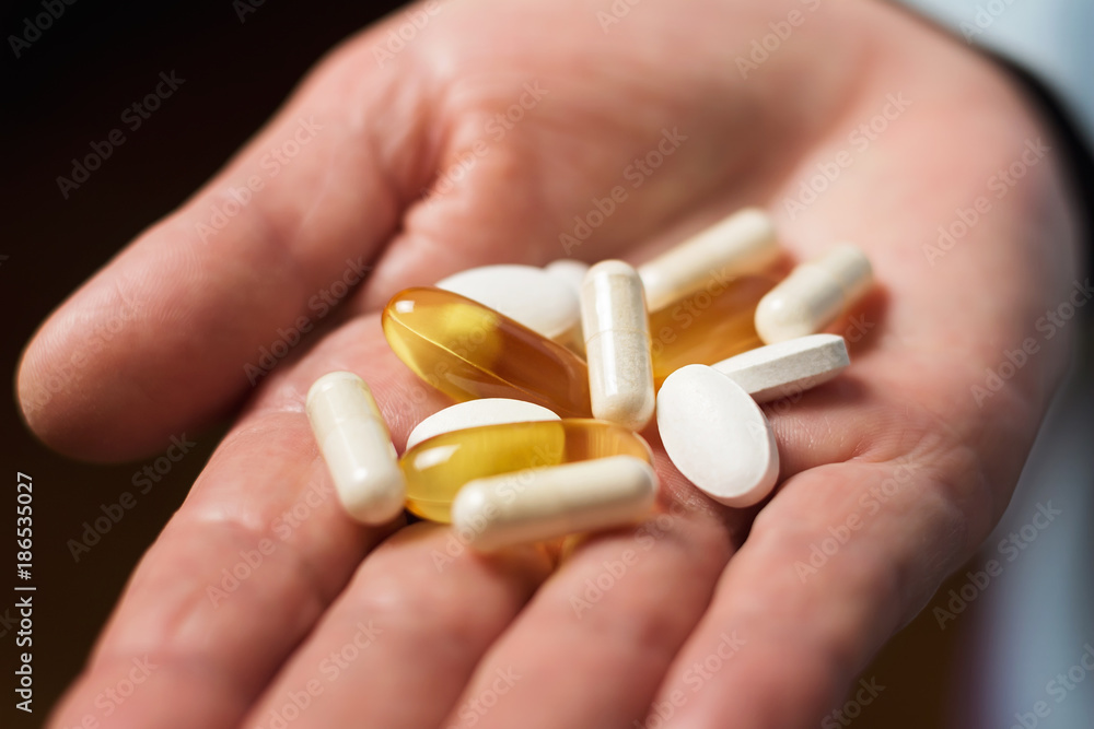 Woman take in the hand variety medication pills, yellow capsules of ...