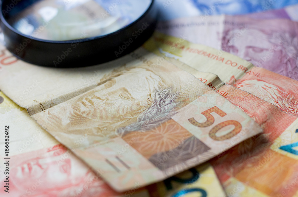 Notas de dinheiro acompanhado de moedas, carteira de trabalho, lupa ...