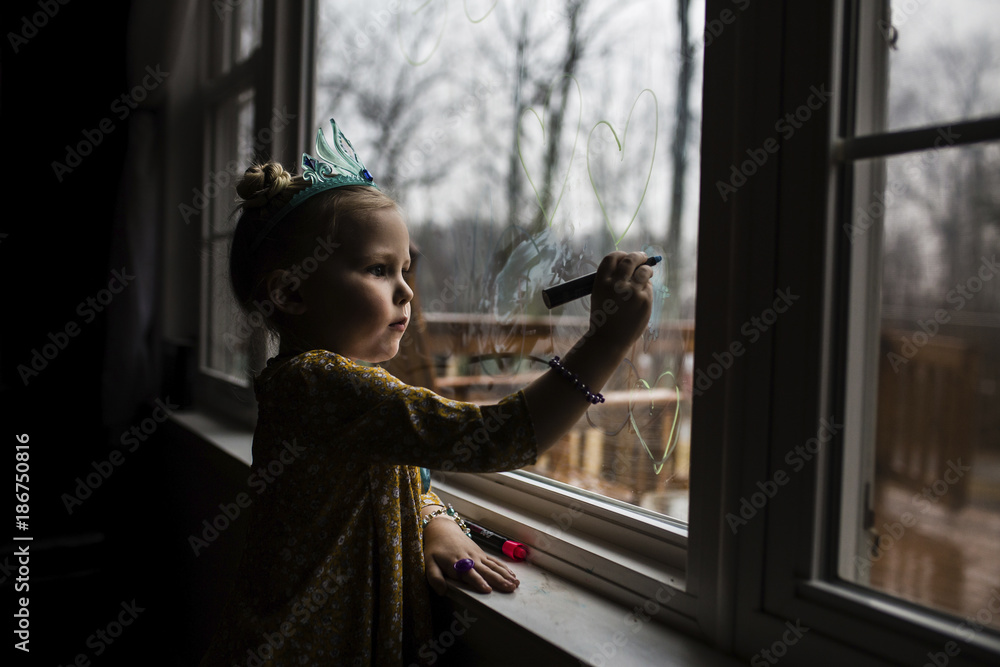 Side view of girl drawing on window Stock Photo | Adobe Stock