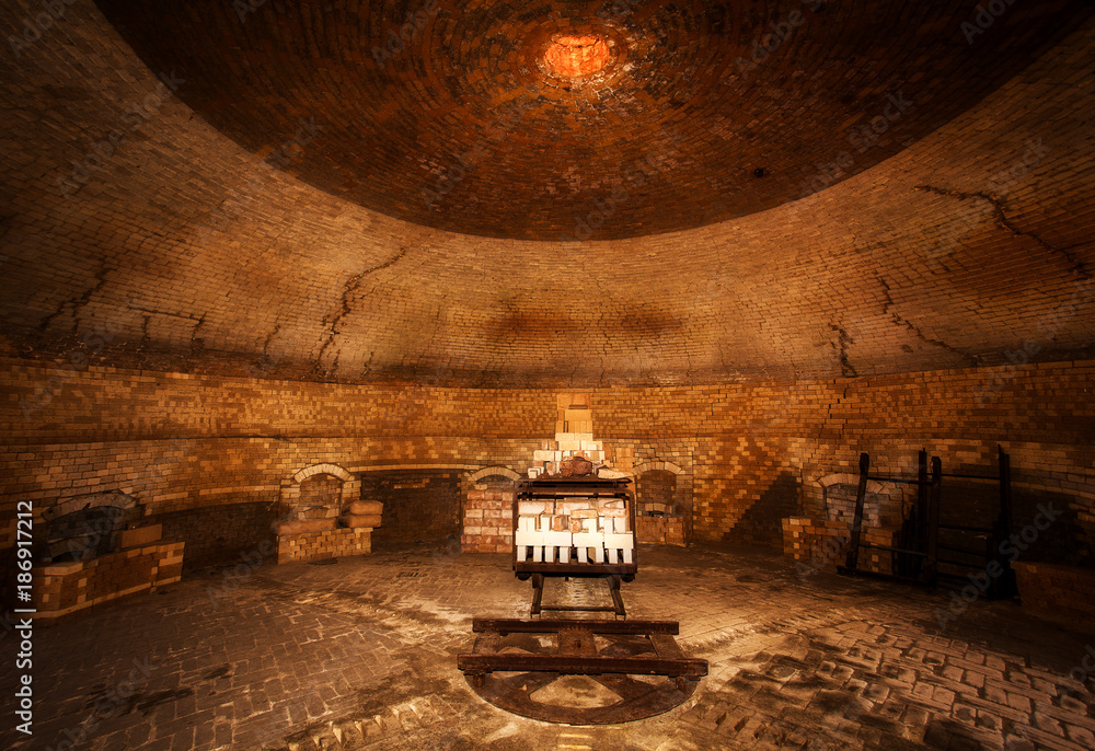 The interior of a large circular brick kiln with multiple freplaces and ...
