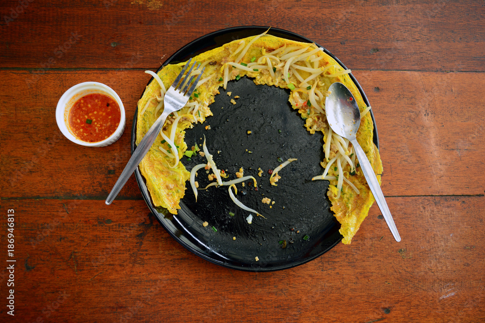 the black dish with fraction of food of finished eat on the brown wood ...