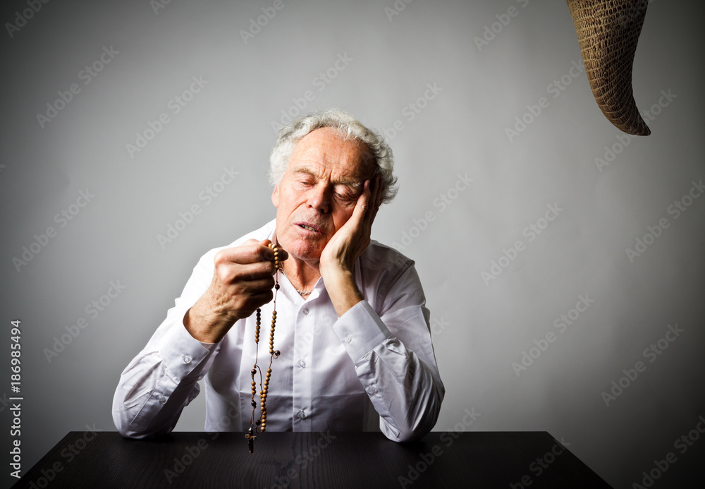 Old man is praying with rosary beads. Prayer and temptation. Devil as ...