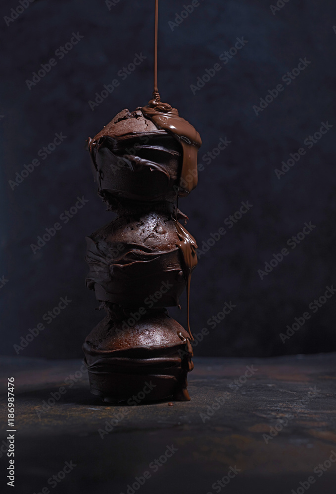 Liquid chocolate dripping on stack of three chocolate muffins Stock ...