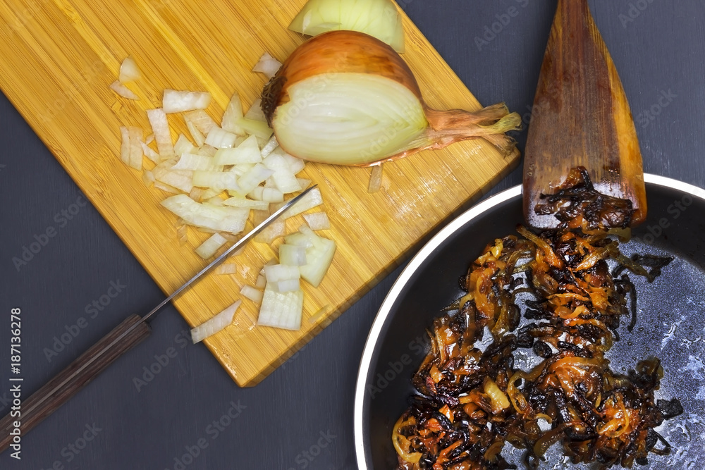 A photo of burnt onion on the teflon pan and wooden spatula. Spoiled ...
