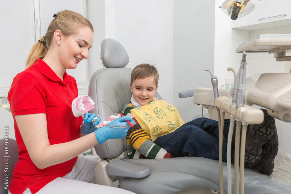 the dentist showing the little boy how to clean the teeth with a ...