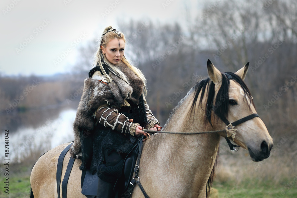 Beautiful viking warrior woman in traditional warrior clothes riding a ...