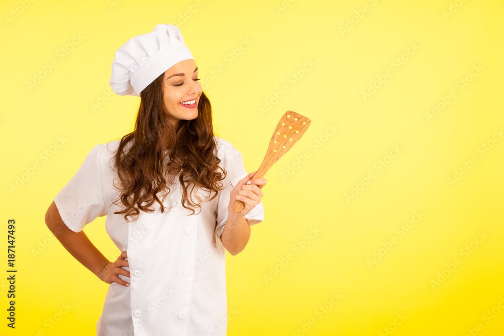 Beautiful chef - cute brunette woman in cook uniform over yellow ...