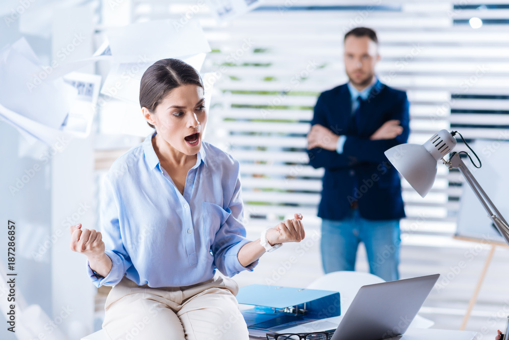 Furious woman. Emotional angry young woman sitting on the table and ...