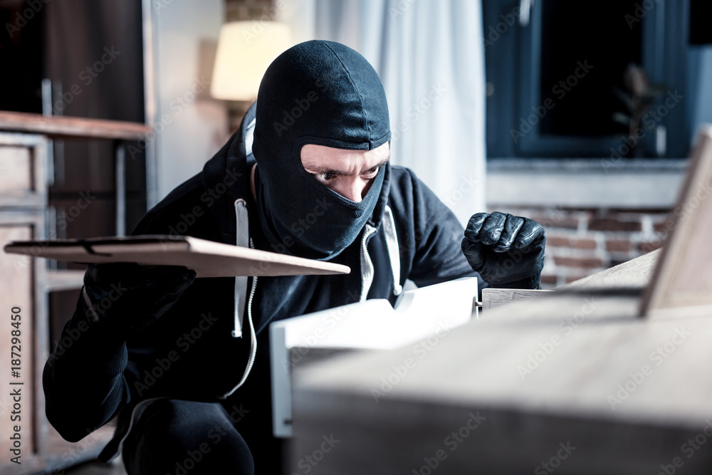 Crime. Dark-eyed skilful masked burglar wearing a uniform and holding a ...