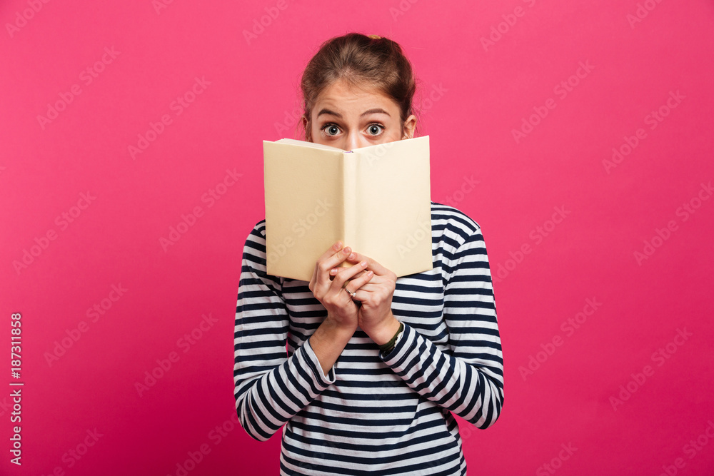 Shocked teenage girl covering face with book. Stock Photo | Adobe Stock