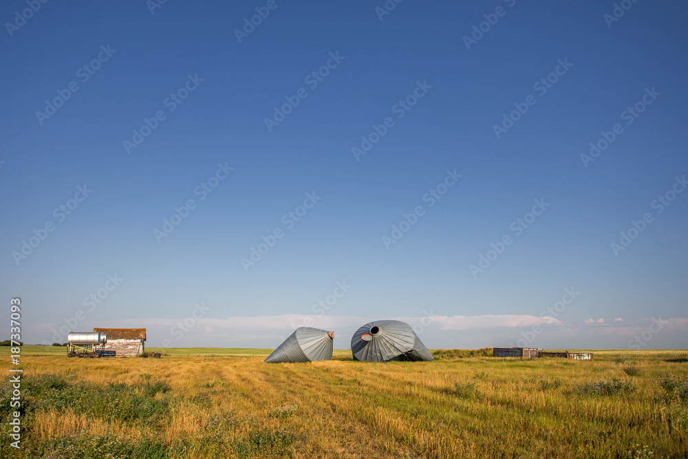 Two crumpled tin storage bins damaged by wind with an old shed and fuel ...