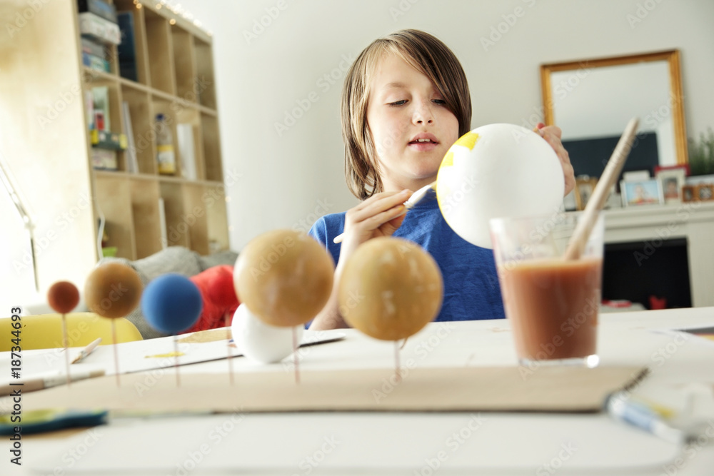 Happy School Boy making a solar system for a school science project at ...