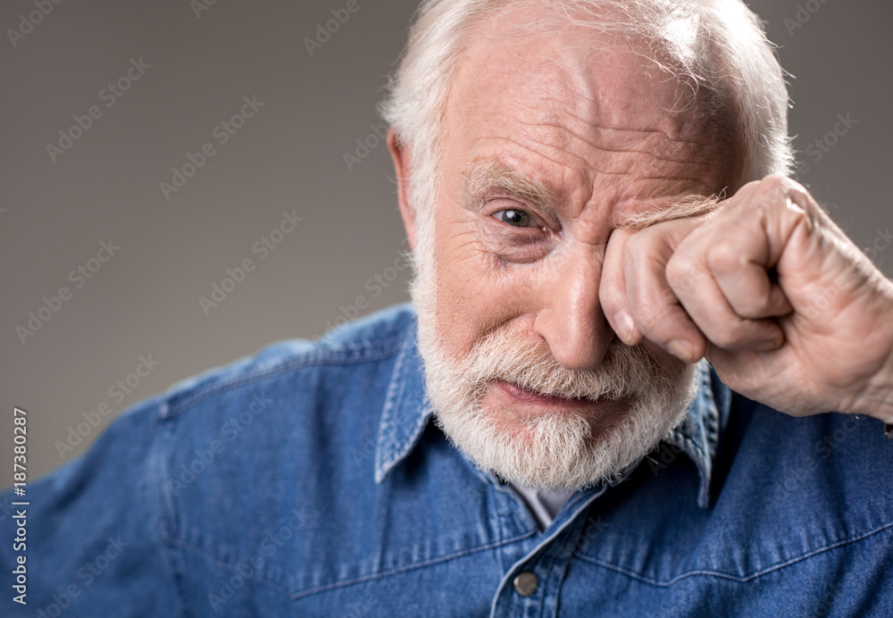 Portrait of upset old man rubbing his eye while crying. Isolated on ...