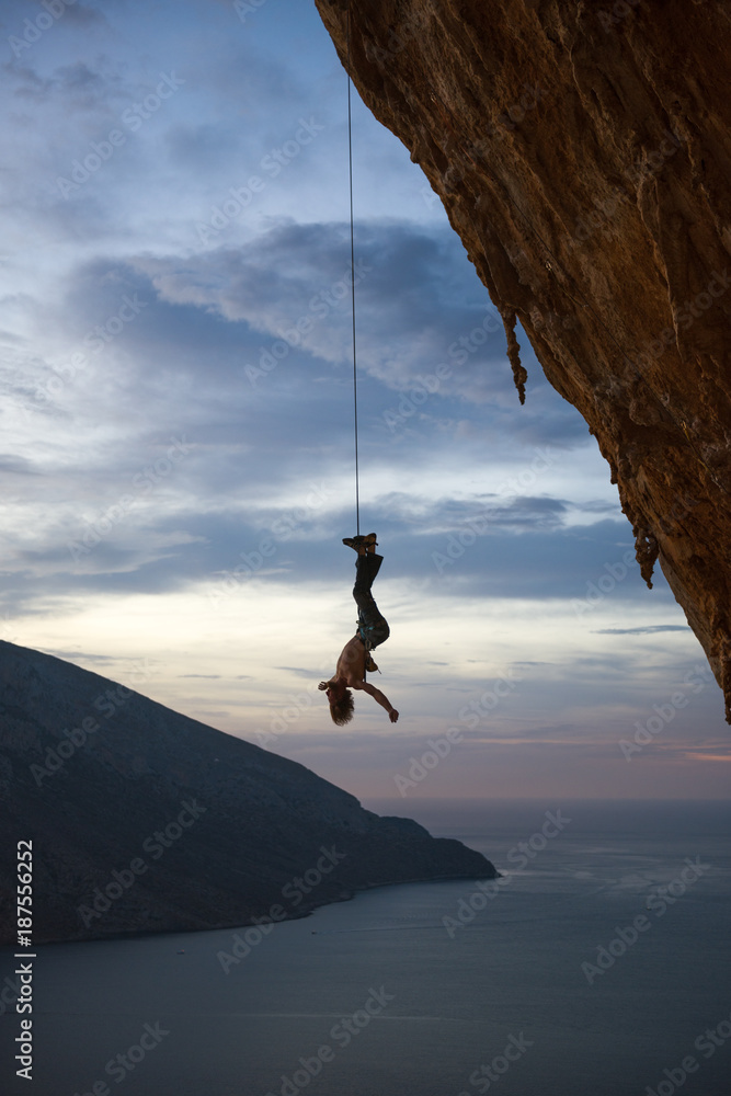 Person's silhouette hanging upside down from steep rock wall foto de ...