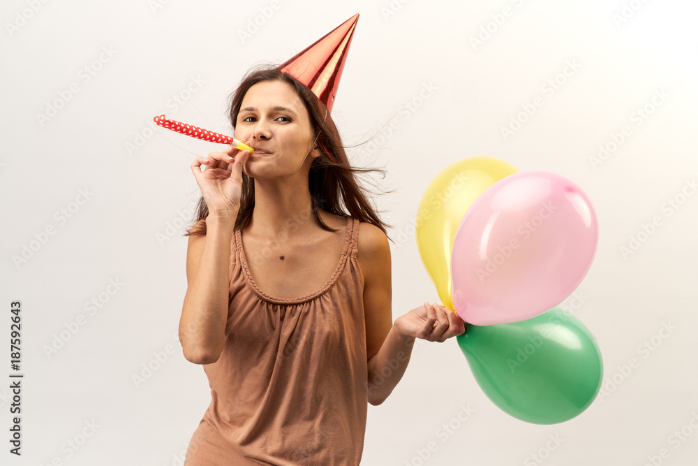 positive cheerful young girl in a party hat and with trumpet and ...